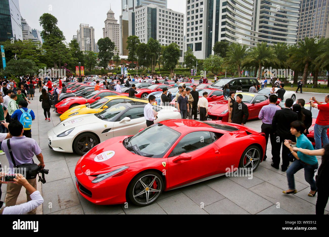 People crowd around Ferrari sports cars lined up during a parade to ...