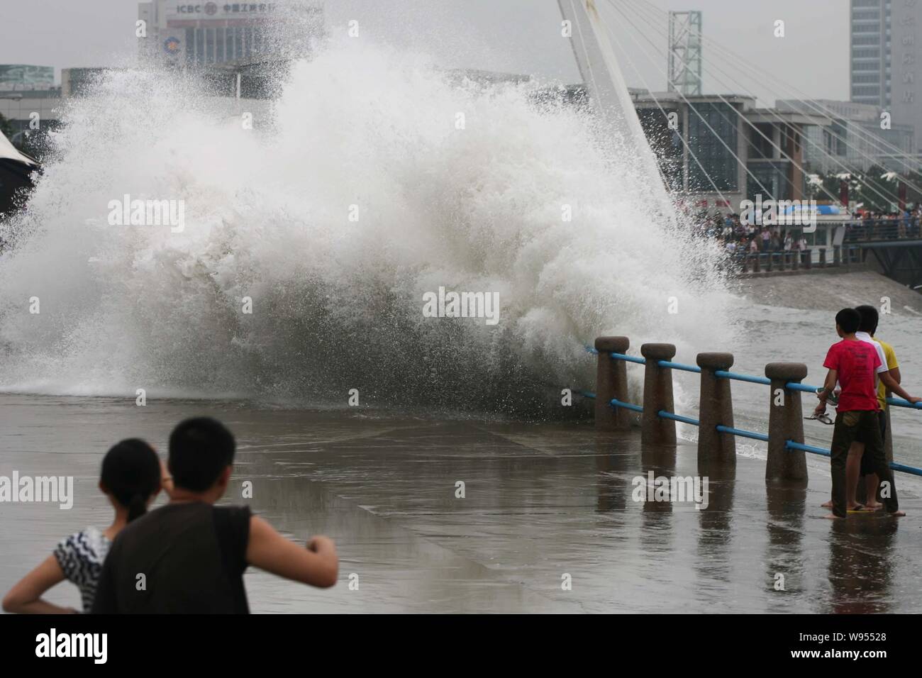 Onlookers look at huge waves caused by Tyhpoon Bolaven hitting the sea ...