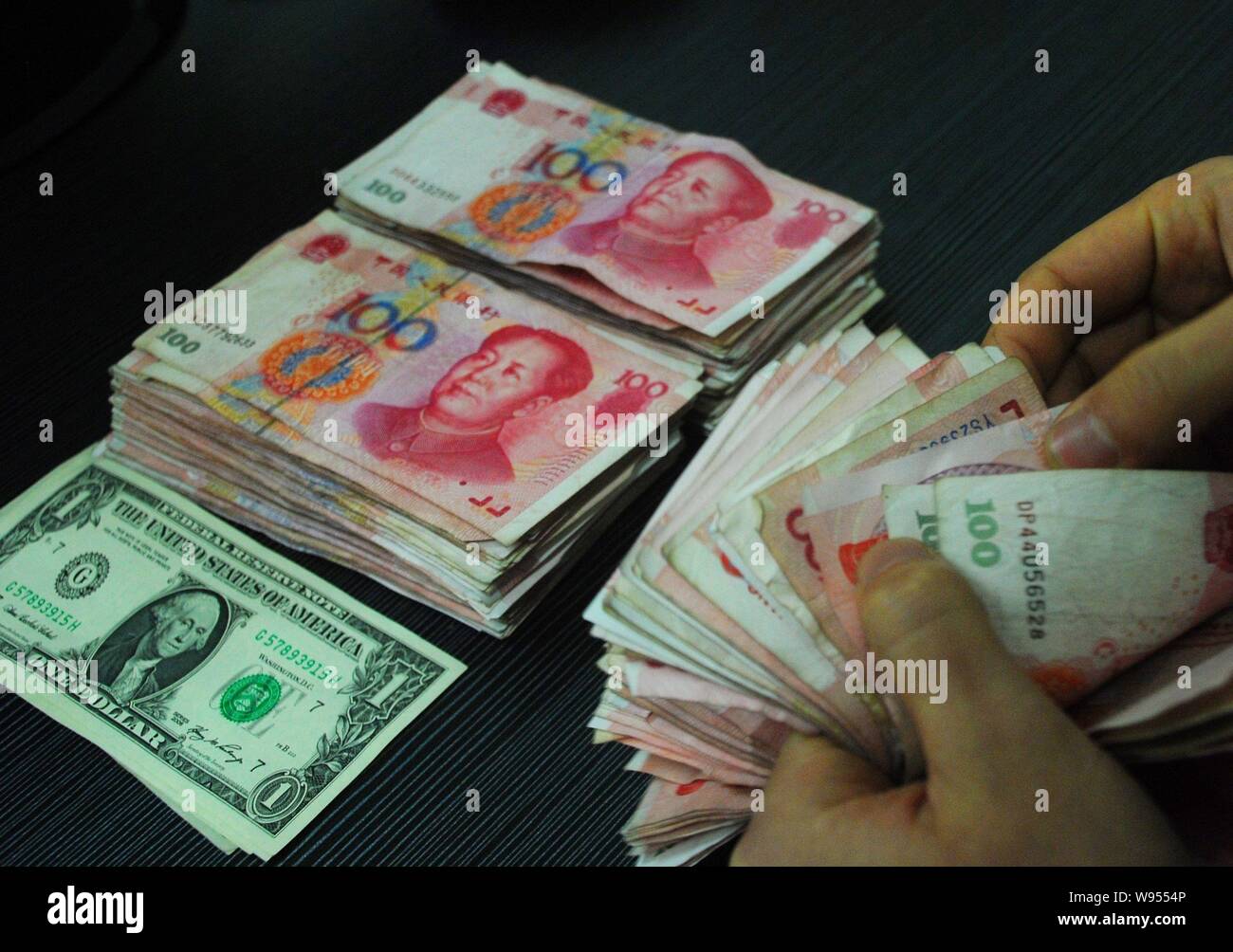 --File--A clerk counts RMB (renminbi) yuan bills over US dollar bills ...
