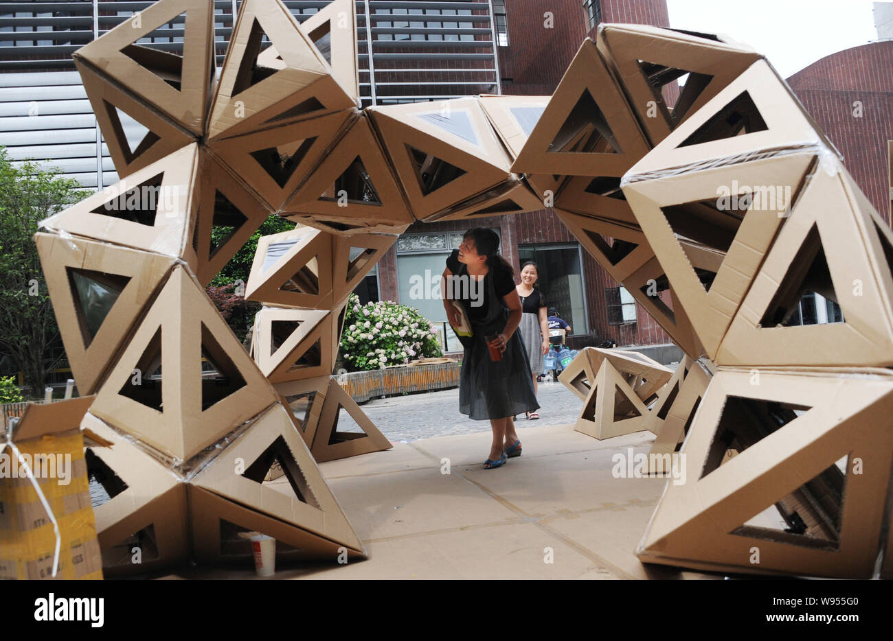 Visitors look at a cardboard building structure at Tongji University in ...
