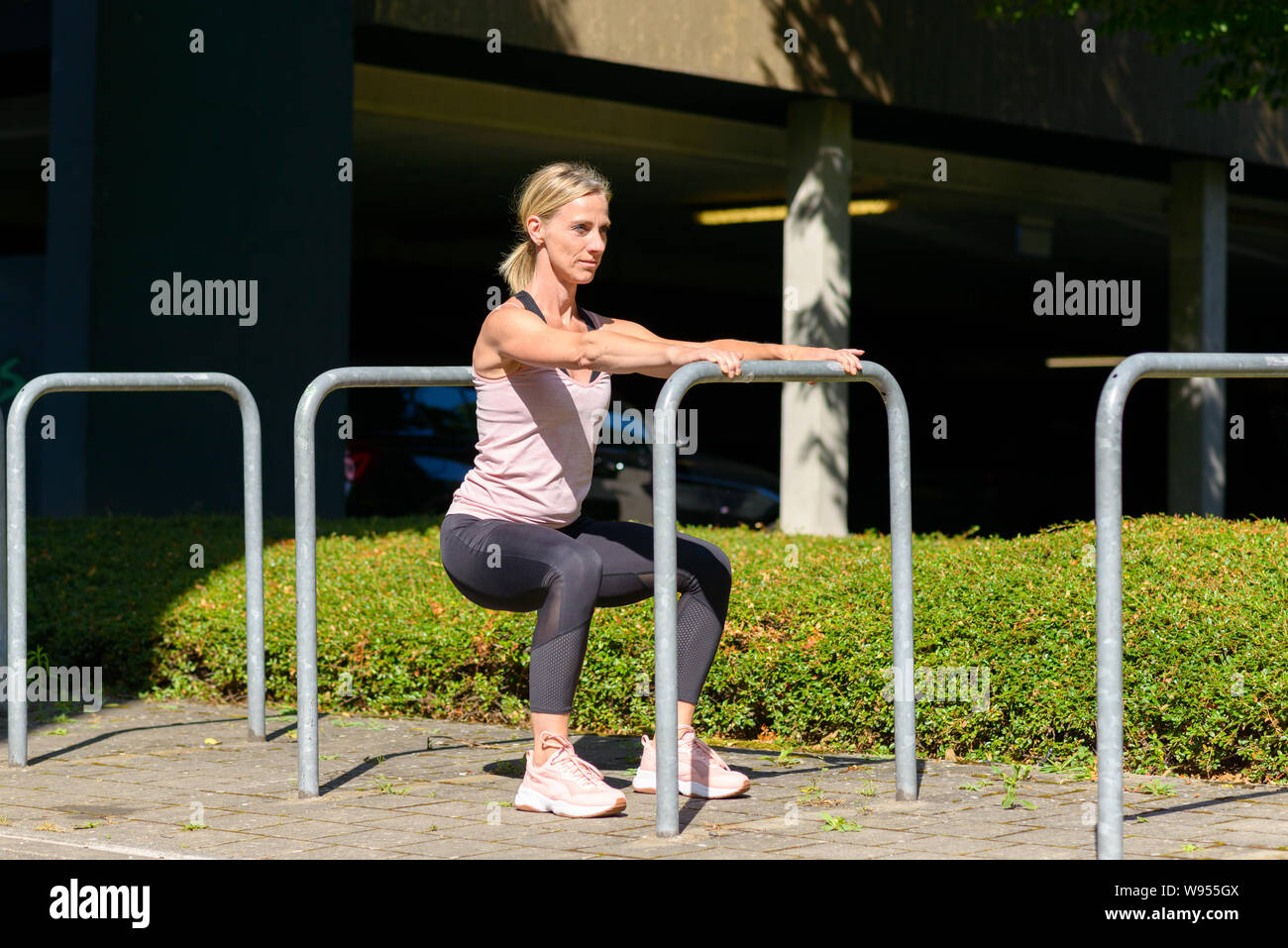 Fit muscular woman working out on bars outdoors on an urban walkway in ...