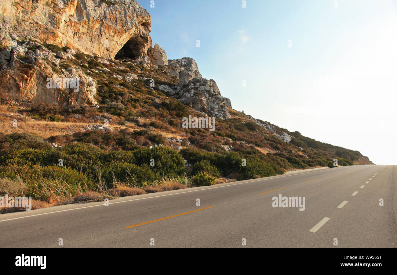 Evening sun shines on sharp rocks by the asphalt road - typical scenery ...