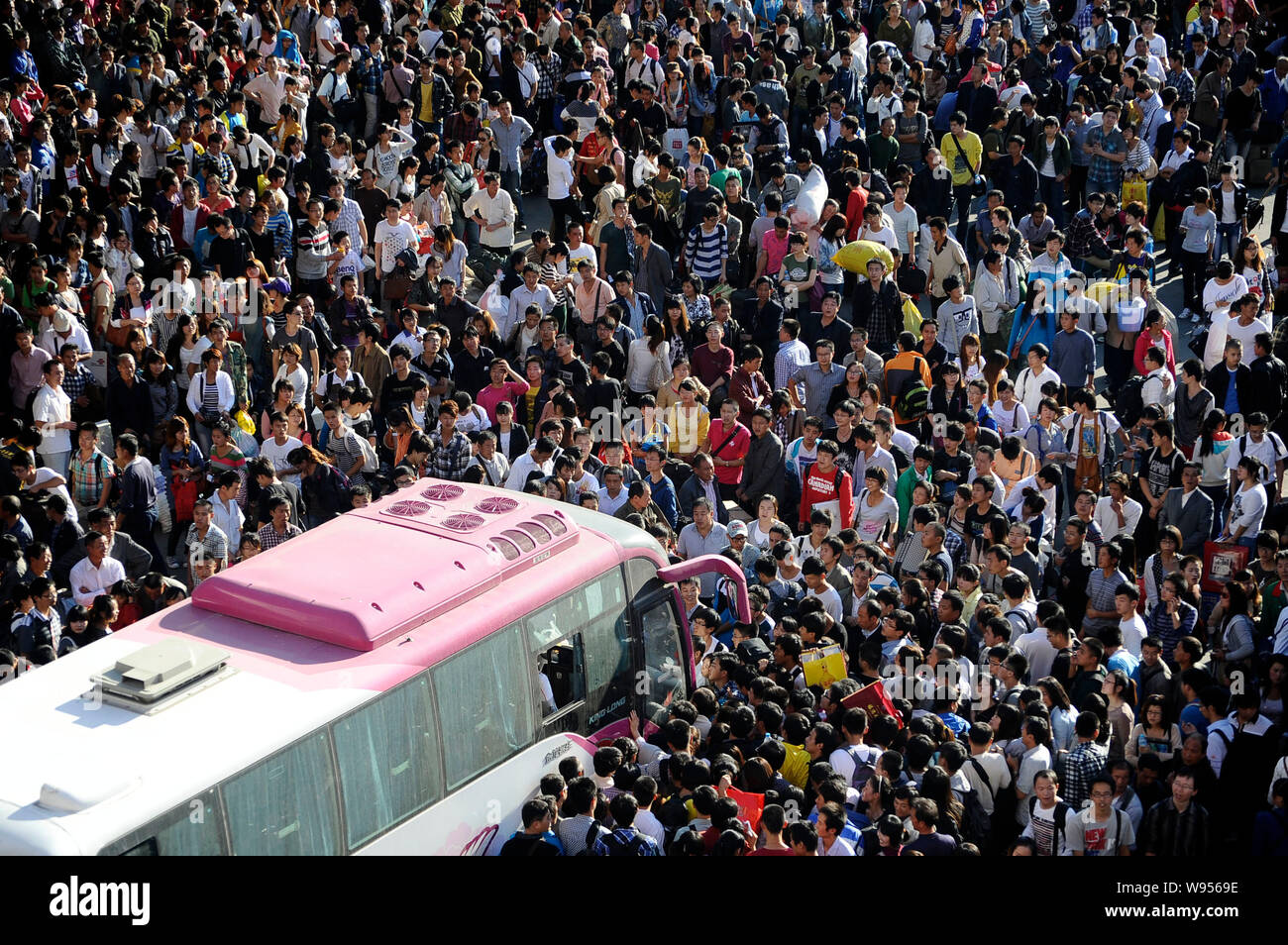 Chinese travelers crowd around buses at a long-distance bus station ...
