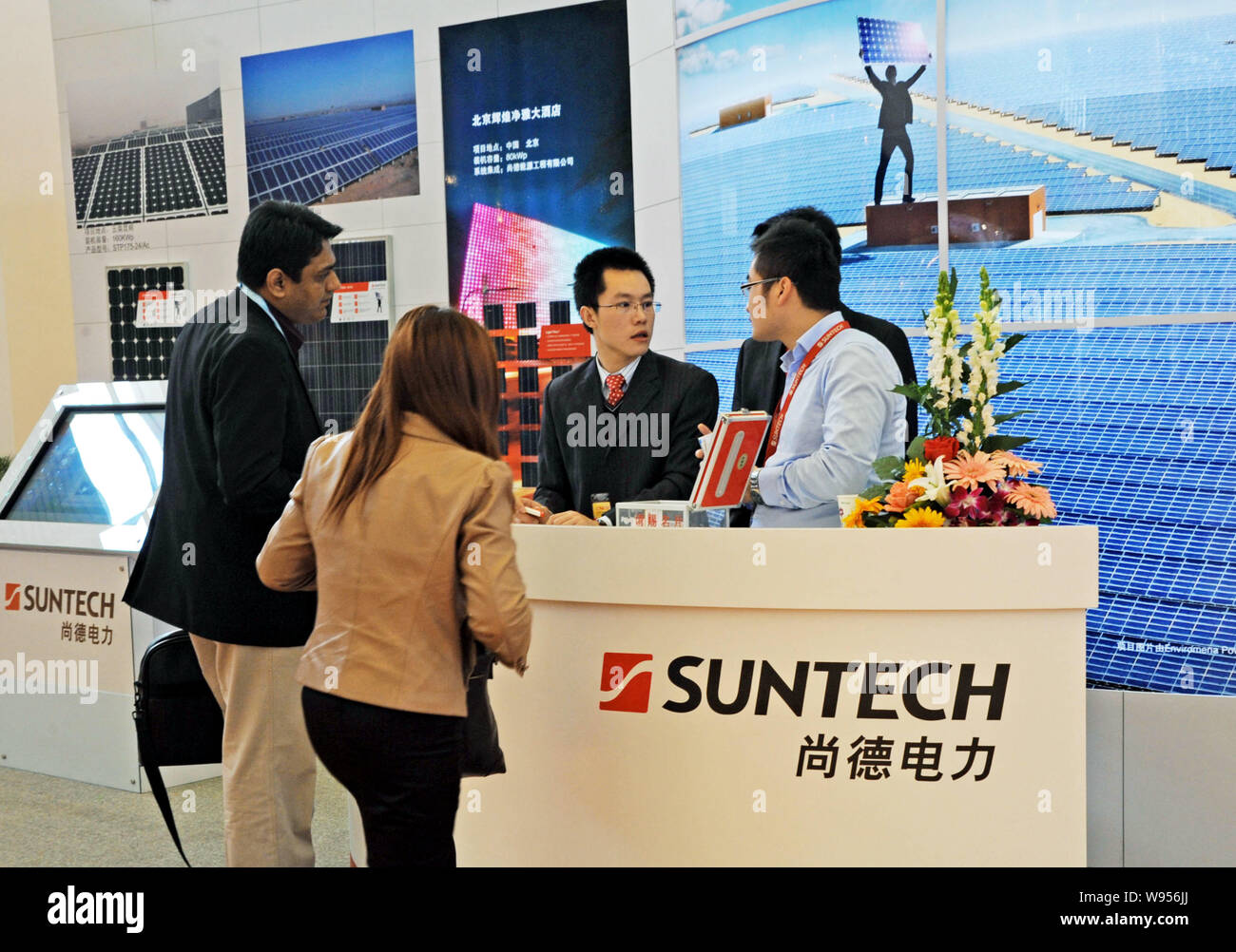--FILE--Employees talk with visitors at the stand of Suntech during a ...