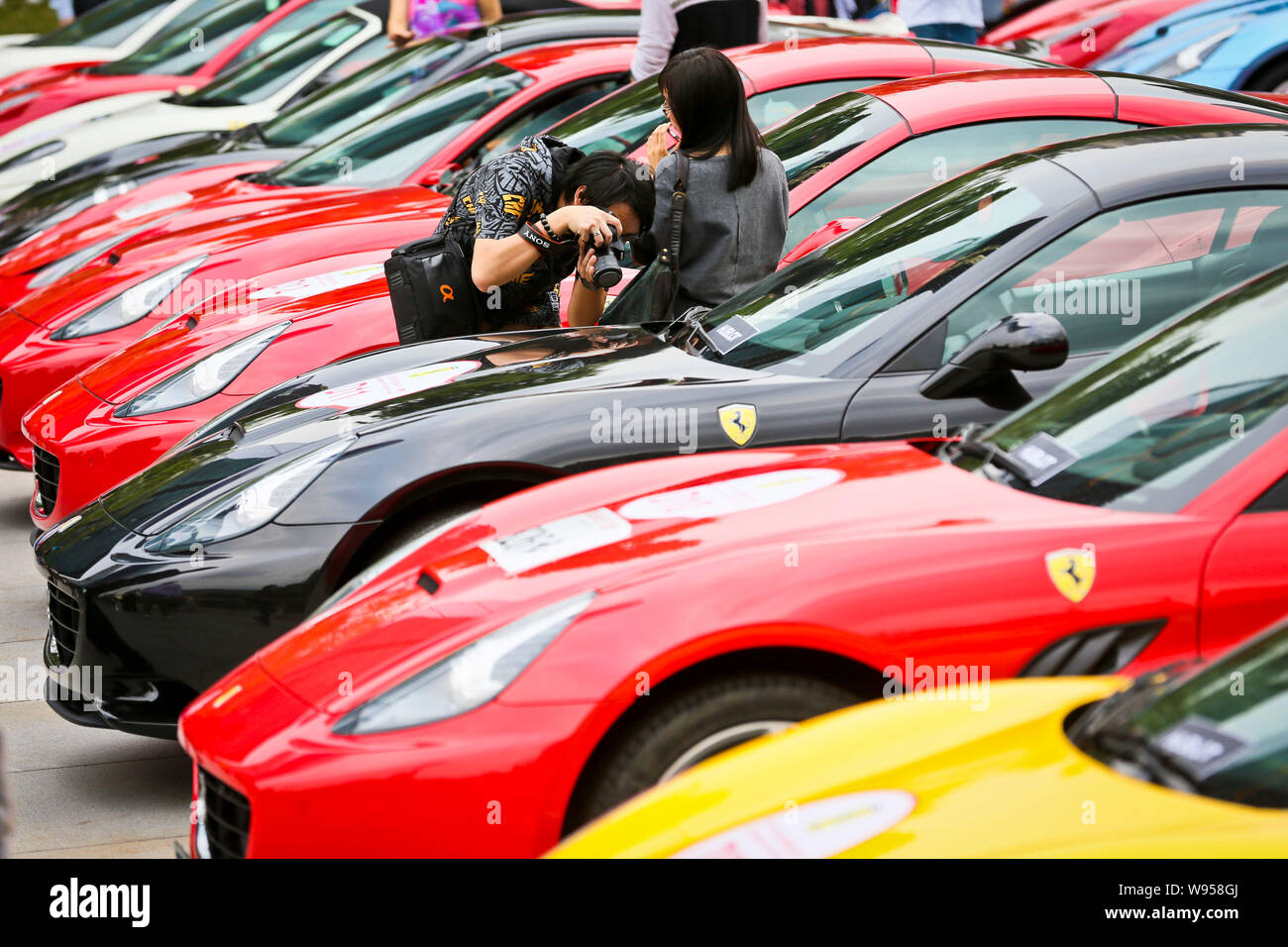 People look at and take photos of Ferrari sports cars lined up during a ...