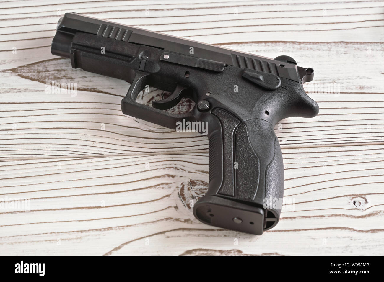 Simple modern black metal gun on white wooden boards table Stock Photo ...