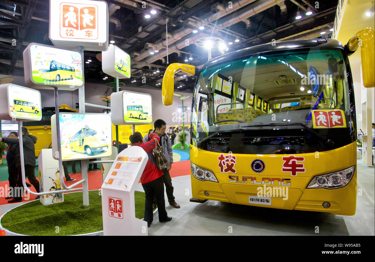 Chinese visitors look at a school bus at the stand of Shanghai Sunlong ...