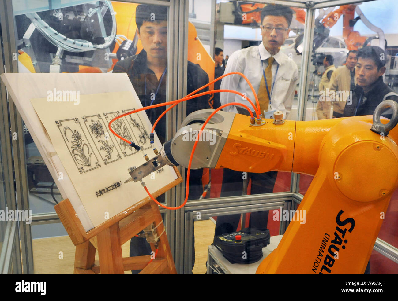 Visitors watch a robot arm of Staubli drawing during the 14th China ...