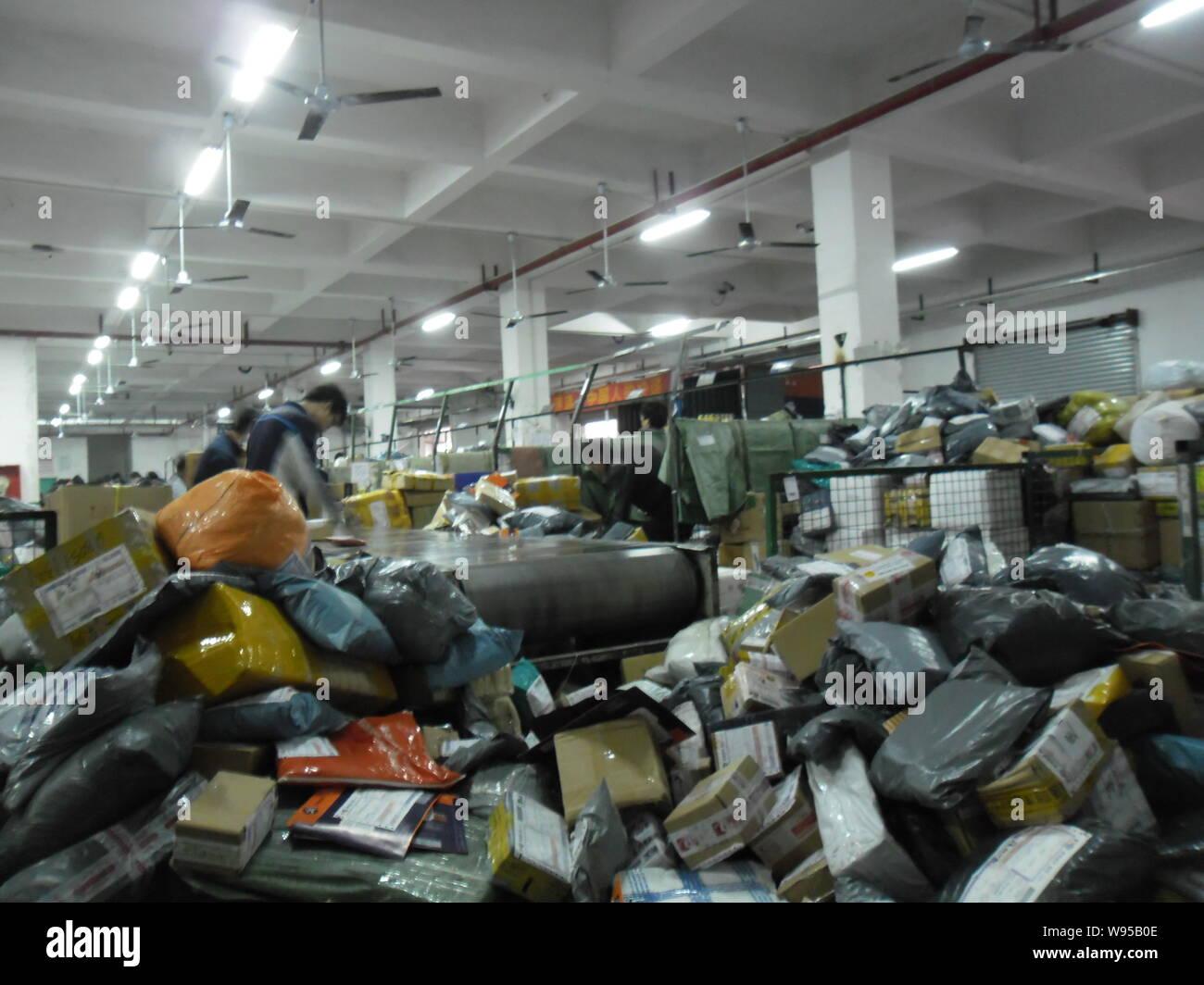 Workers sort parcels at a sorting station of YTO Express in Shenzhen ...