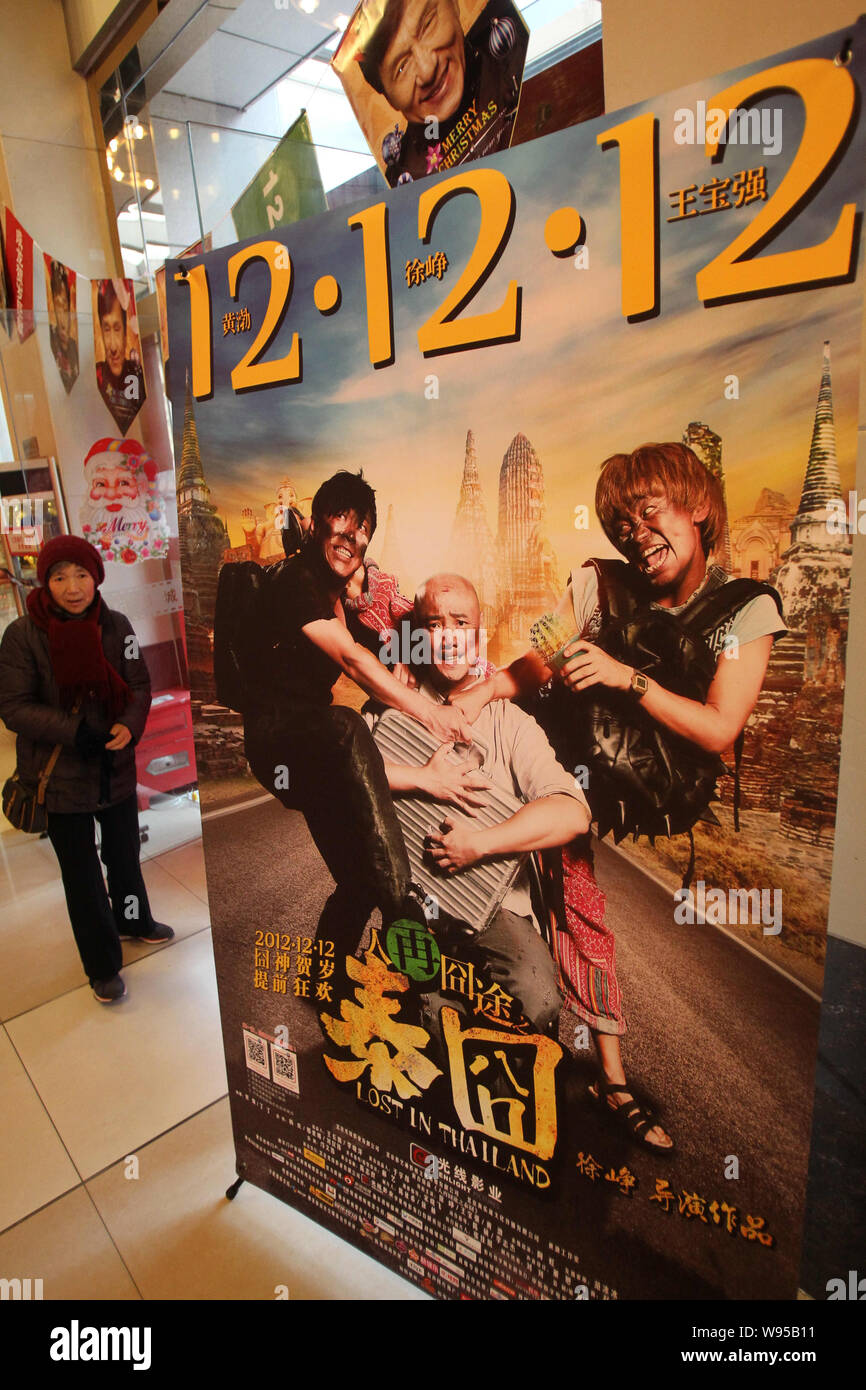 A Chinese filmgoer stands next to a poster of the movie, Lost in ...