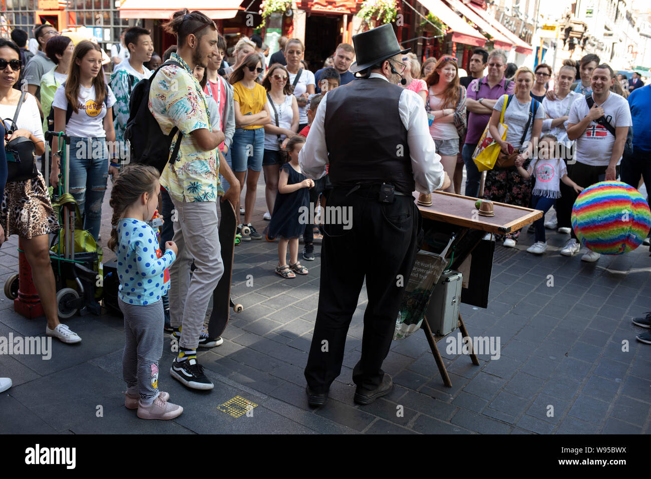 Street scene as a crowd of tourists of all ages gather to watch a ...