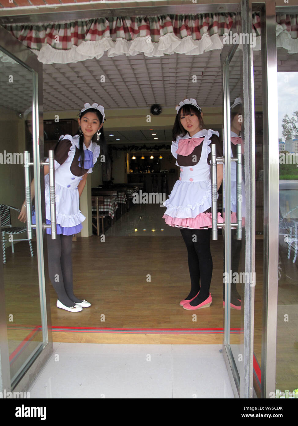 Waitresses in maid uniforms welcome customers at a maid-themed ...