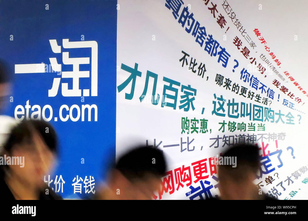 --FILE--Pedestrians walk past an advertisement for etao.com of Alibaba ...