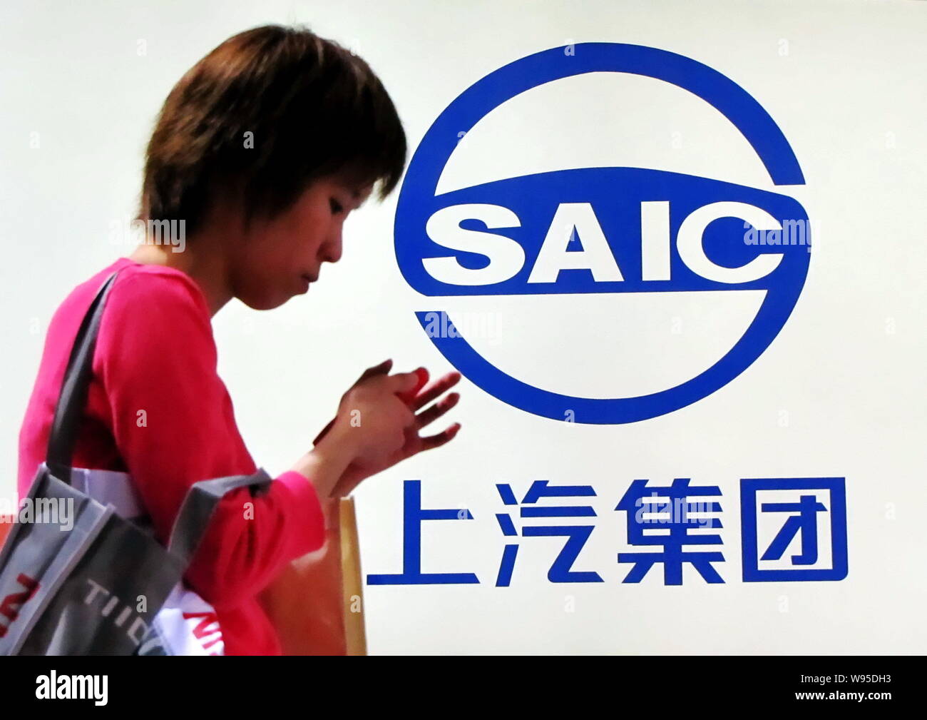--FILE--A Chinese woman walks past the logo of SAIC during the 14th ...