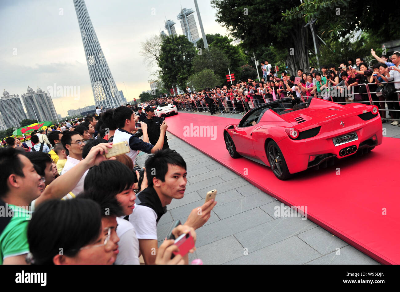 People look at Ferrari sports cars during a parade to celebrate the ...