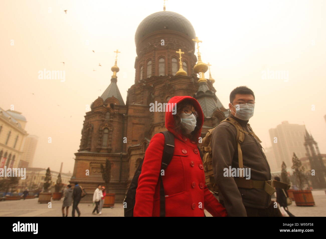 Masked pedestrians walk on the road in a sandstorm in Harbin, northeast ...