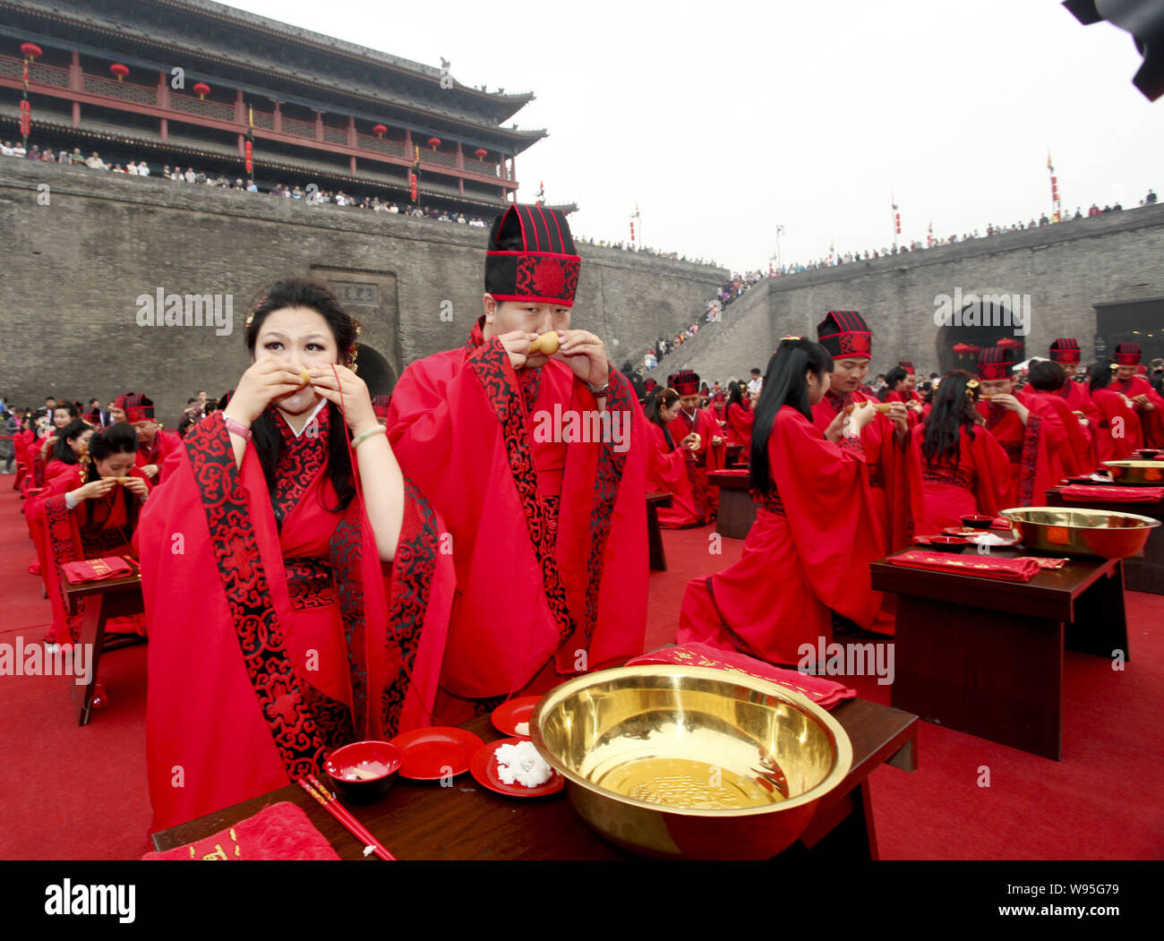 Couples of newlyweds dressed in traditional Han costumes drink as part ...