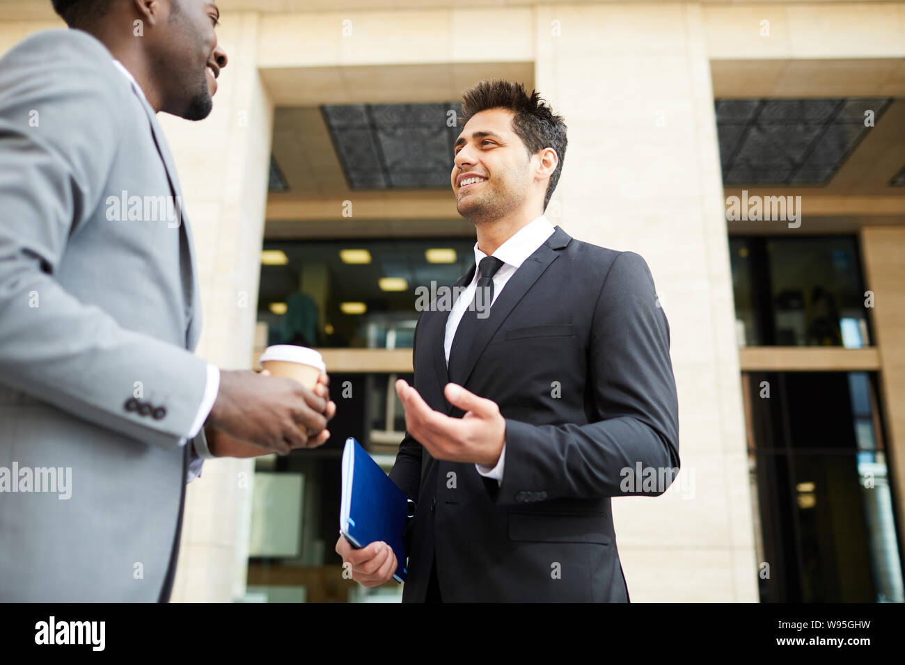 Young businessman in black suit smiling and explaining something to his ...