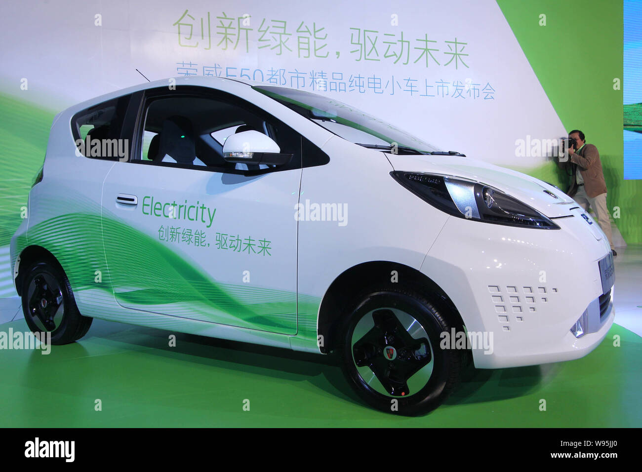 A visitor takes photos of a Roewe e50 electric car of SAIC Motor during ...