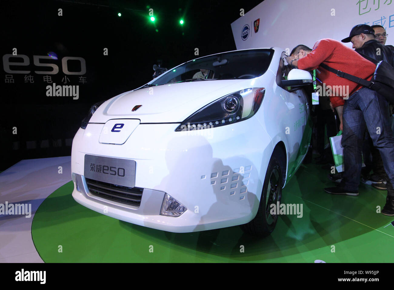 Visitors look at a Roewe e50 electric car of SAIC Motor during a launch ...