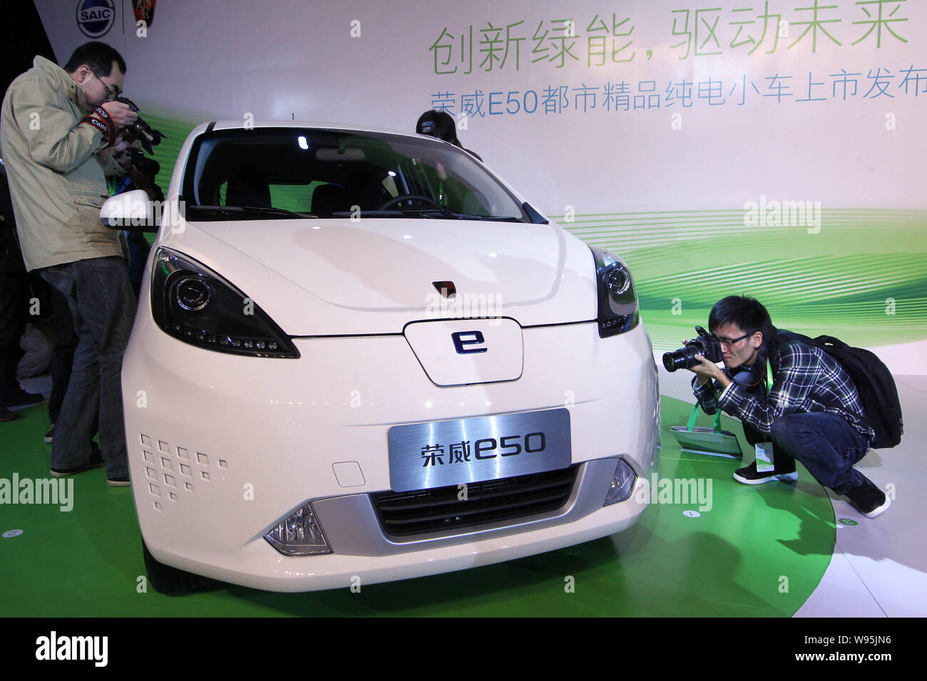 Visitors take photos of a Roewe e50 electric car of SAIC Motor during a ...