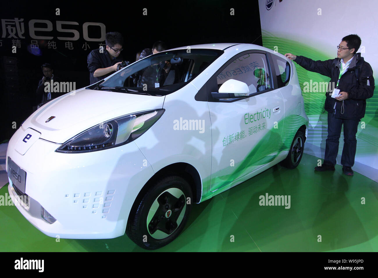 Visitors take photos of a Roewe e50 electric car of SAIC Motor during a ...
