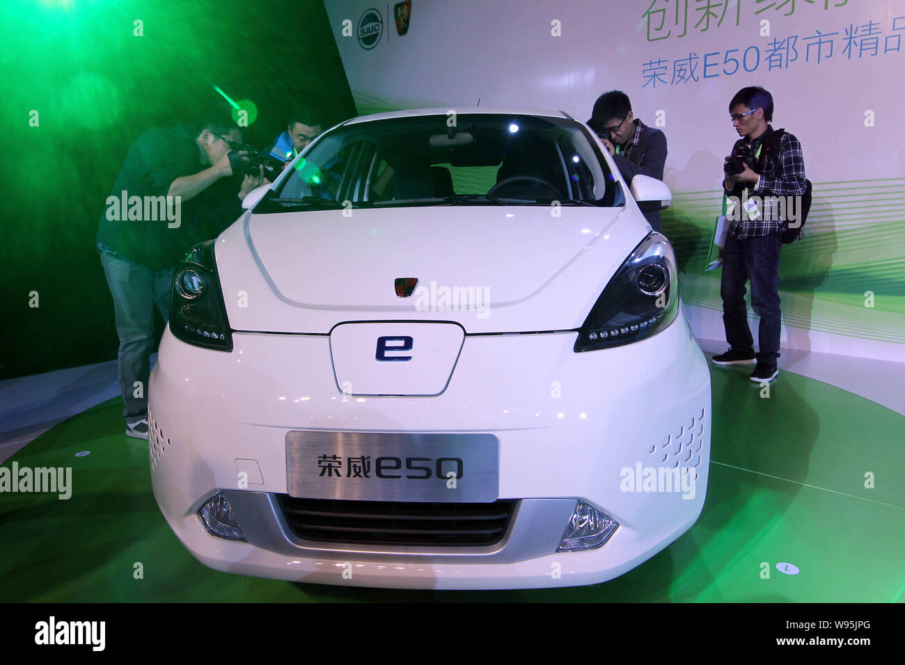 Visitors take photos of a Roewe e50 electric car of SAIC Motor during a ...