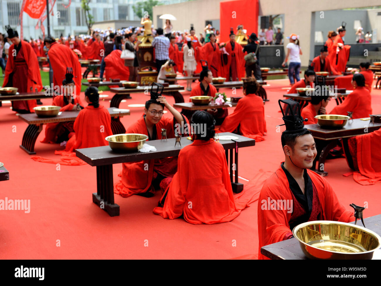 Couples of newlyweds dressed in traditional Han costumes sit face to ...