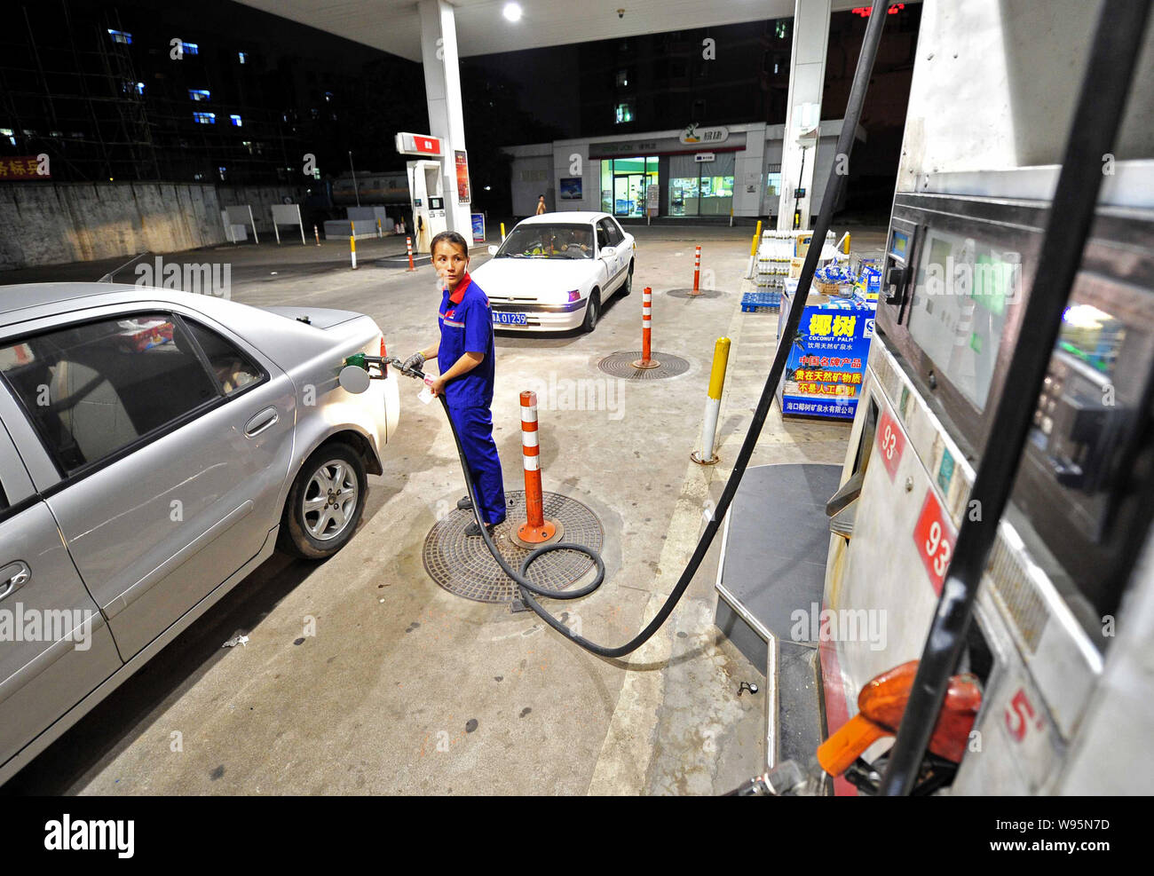 A Chinese worker refuels a car is at a gas station in Haikou city ...