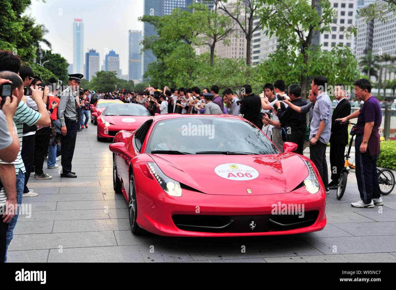 People look at Ferrari sports cars during a parade to celebrate the ...