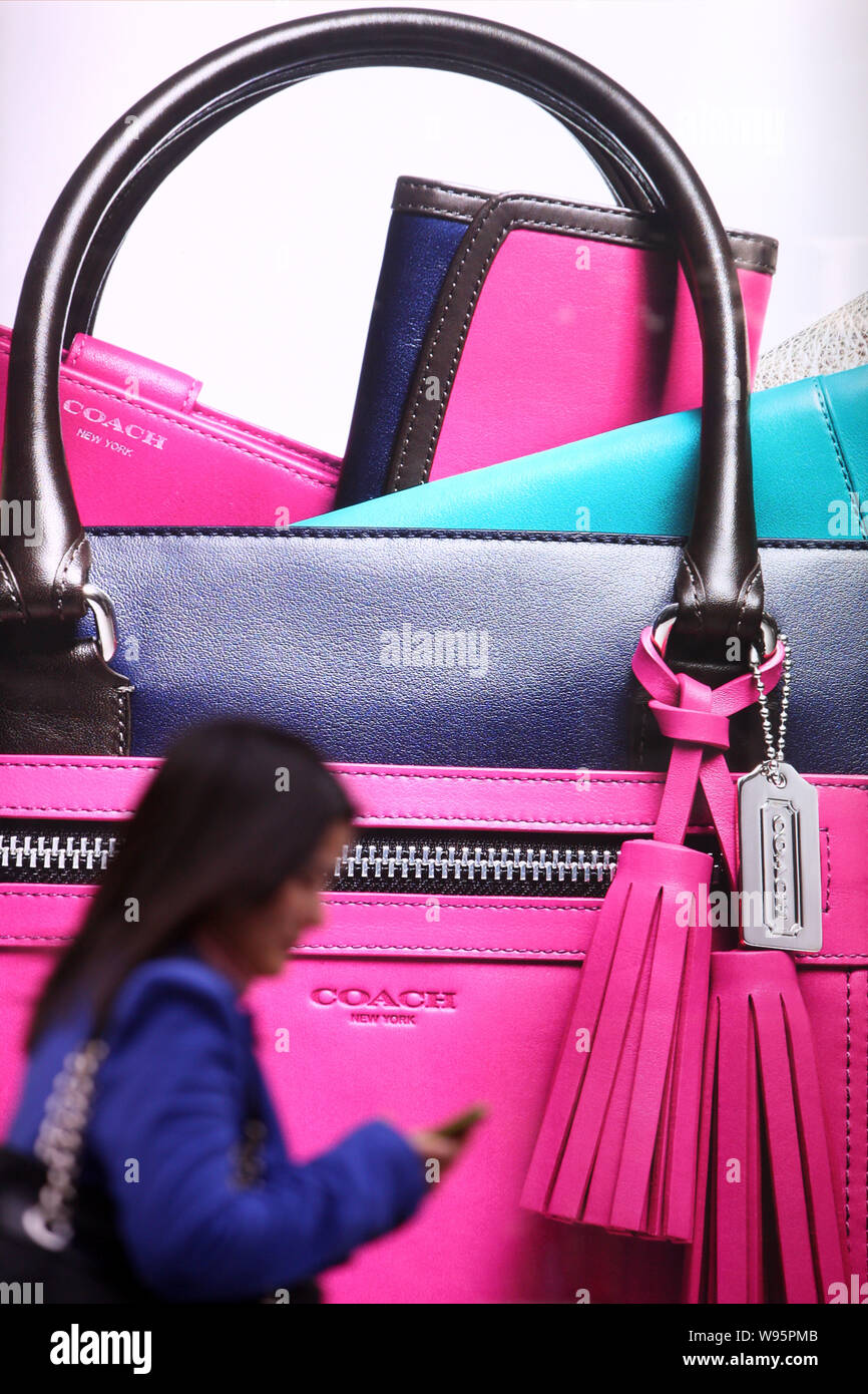 A young Chinese woman walks past a Coach store in Shanghai, China, 24 ...