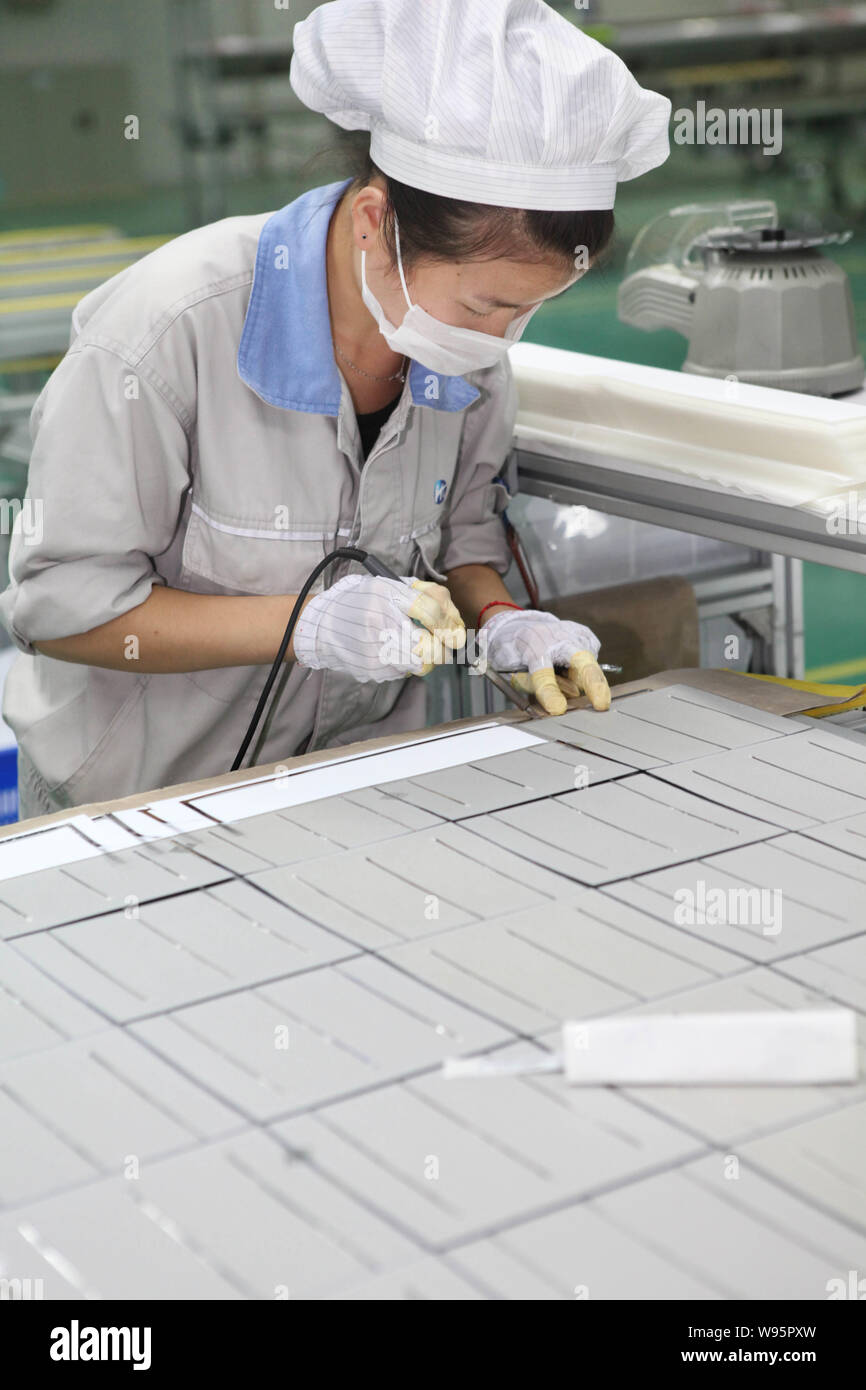 A Chinese worker welds PV (photovoltaic) cells for making solar panels ...