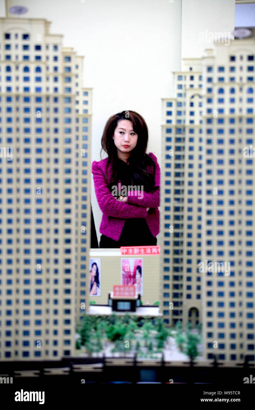 A young Chinese woman looks at model buildings at the sales center of a ...