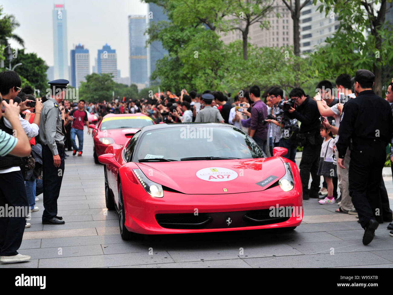 People look at Ferrari sports cars during a parade to celebrate the ...