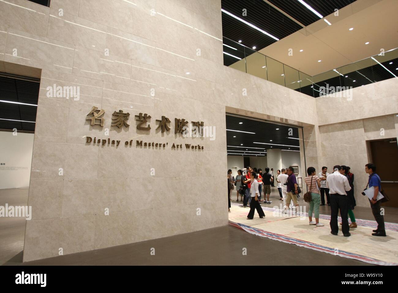 Visitors look at artworks in the exhibition hall for the display of ...