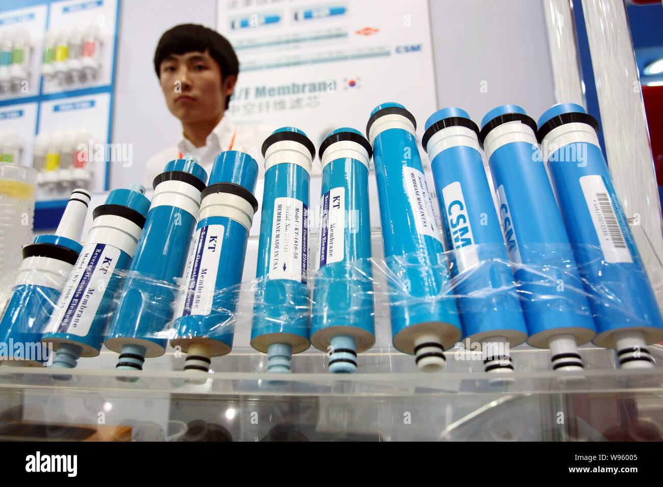 A Chinese staff member poses behind filters of water purifiers during ...