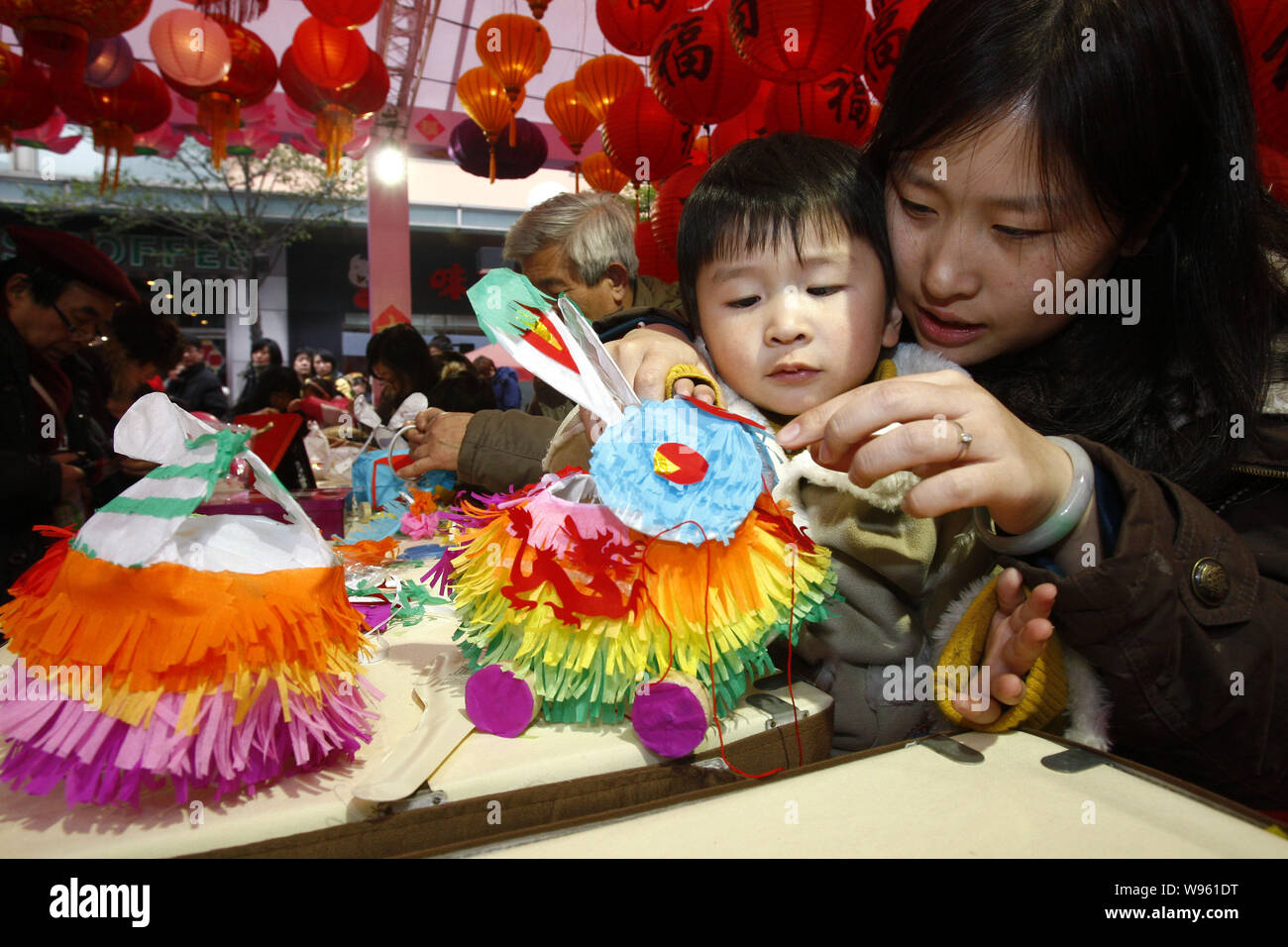 A Chinese woman helps her child to make a rabbit-shaped lantern to ...