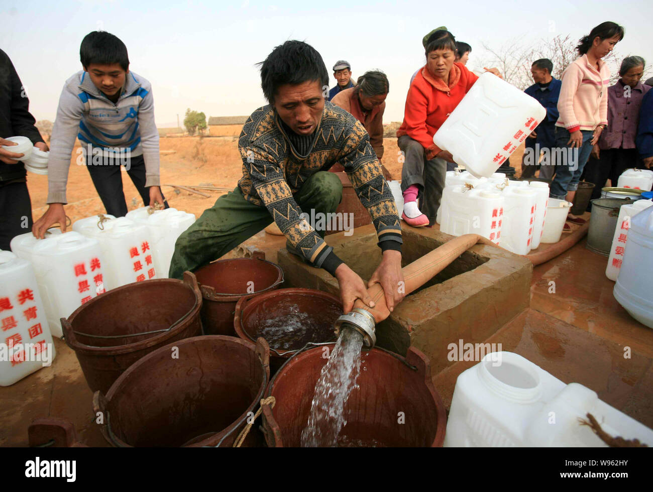 Chinese villagers line up to fill up their buckets with water at a ...