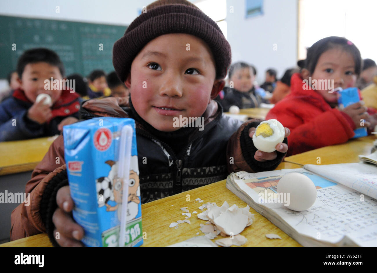 --FILE--Young Chinese students eat eggs and drink milk during a break ...