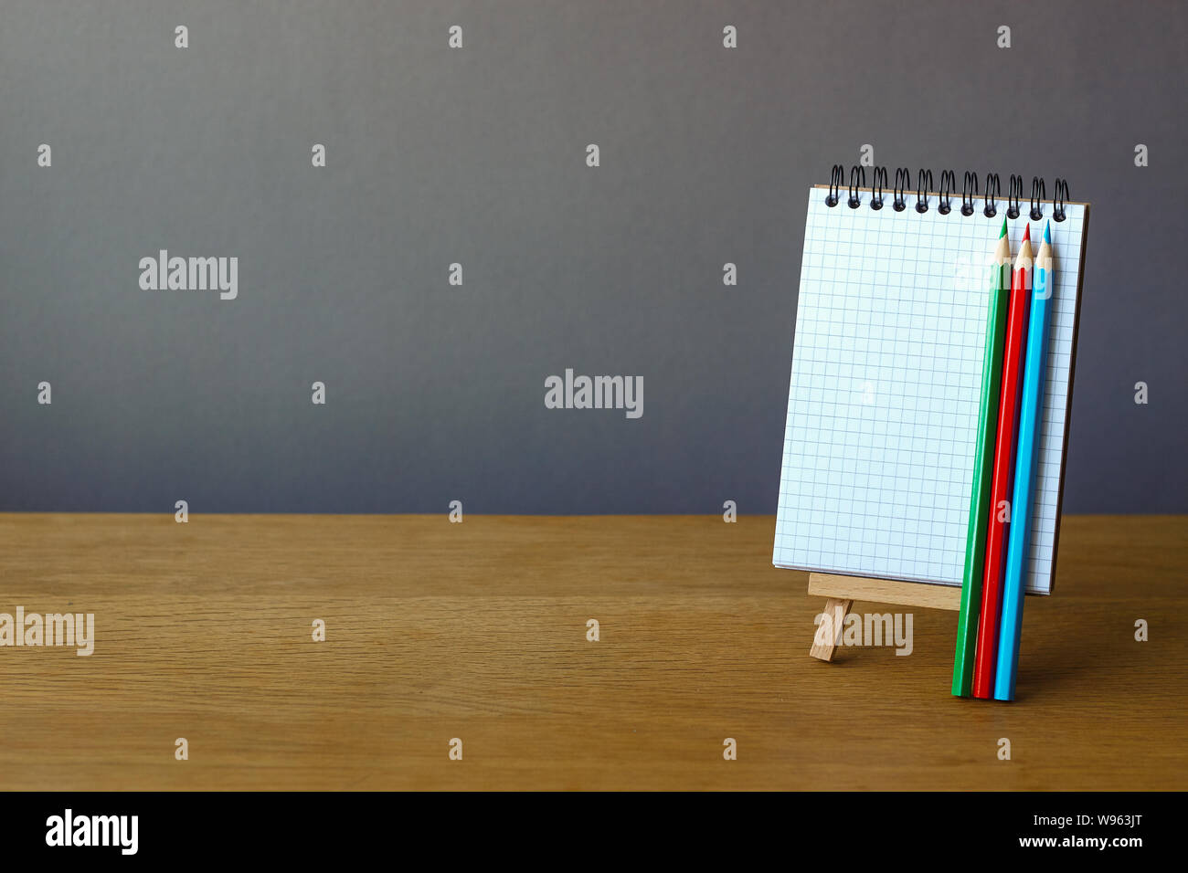 Back to school concept, open notebook on a miniature easel and three ...