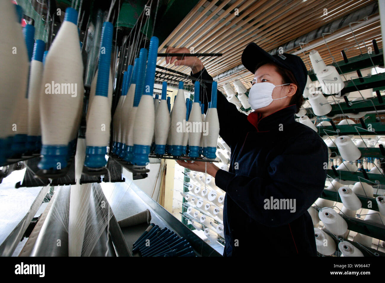 --FILE--A female Chinese worker installs spindles of yarn on a spinning ...