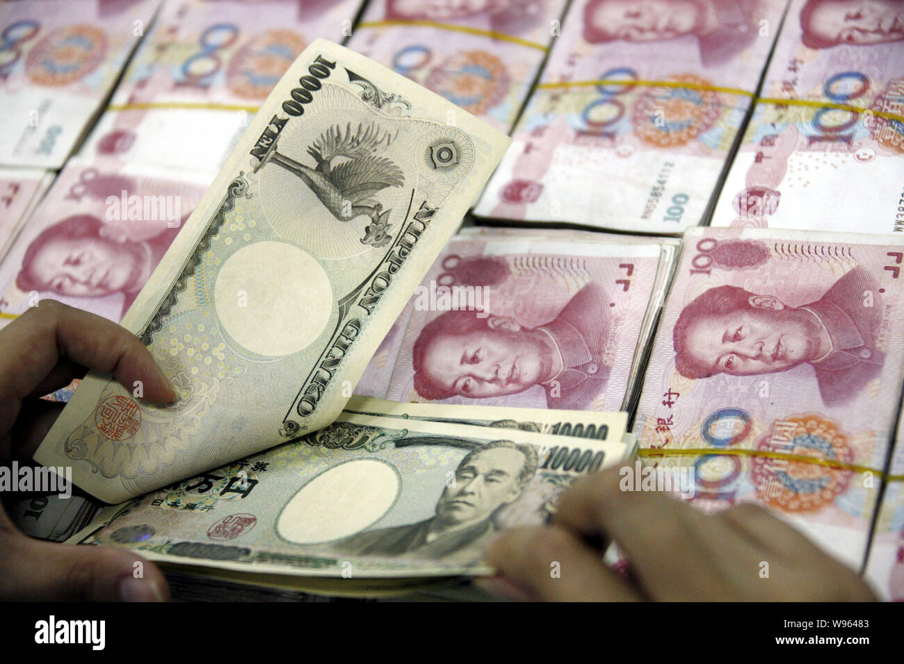 A Chinese clerk counts Japanese yen bills over RMB (renminbi) yuan ...