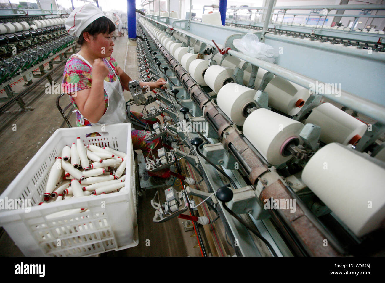 A female Chinese worker handles the production of yarn on a spinning machine at the textile ...