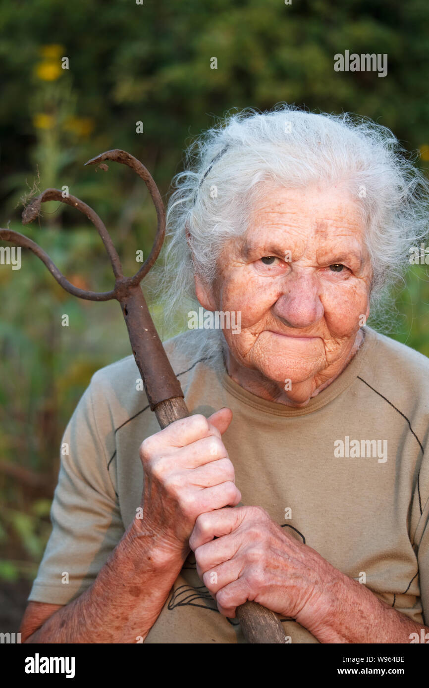 Closeup portrait of an old woman with gray hair holding a rusty ...
