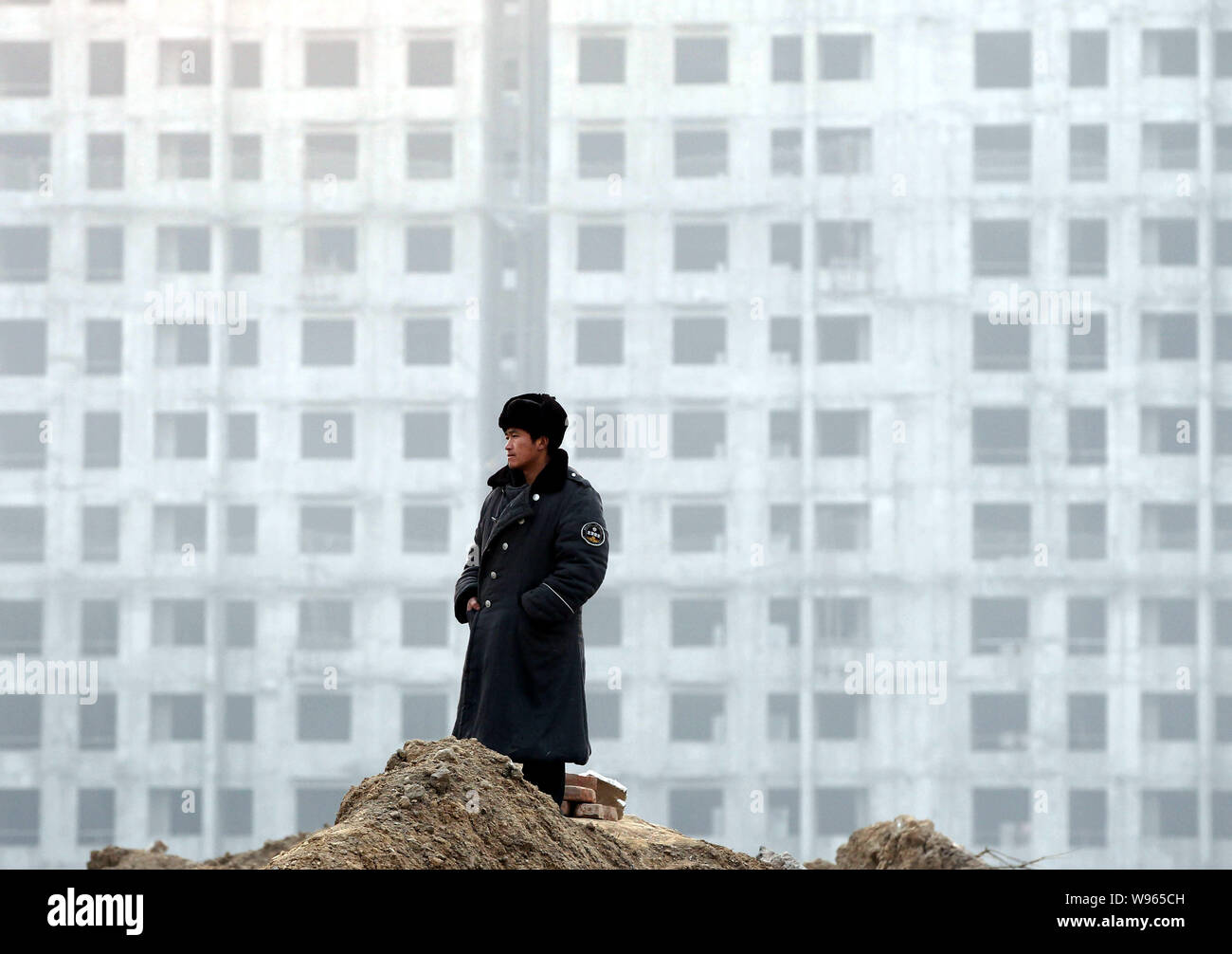 --FILE--A Chinese security guard stands in front of new residential ...