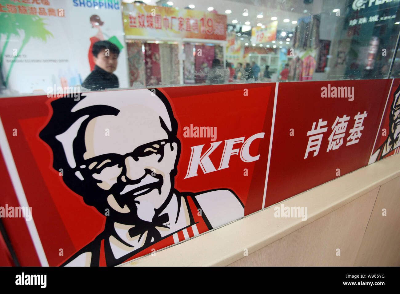 A pedestrian walks past a KFC fastfood restaurant in Shanghai, China ...