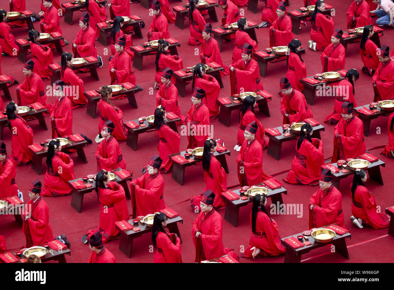 Couples of newlyweds dressed in traditional Han costumes kneel and bow ...