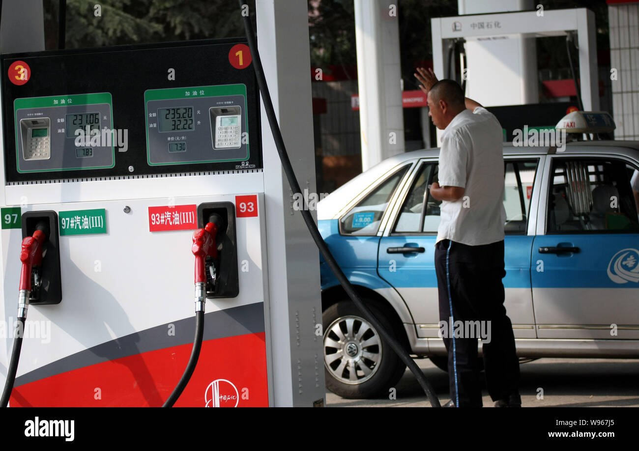 --FILE--A Chinese taxi driver stands besides his car being refueled at ...