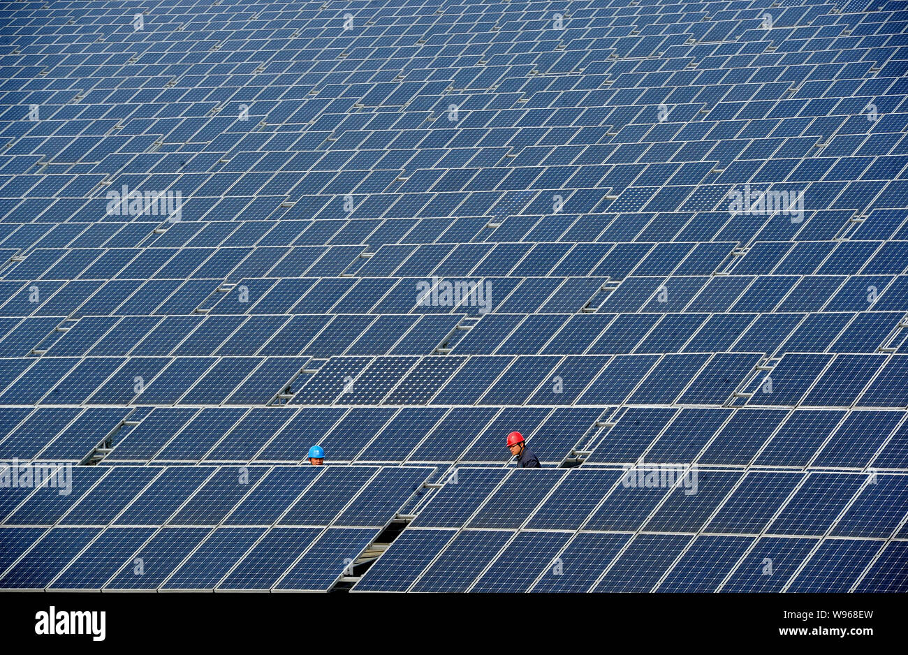 Chinese workers check arrays of solar panels at a photovoltaic power ...