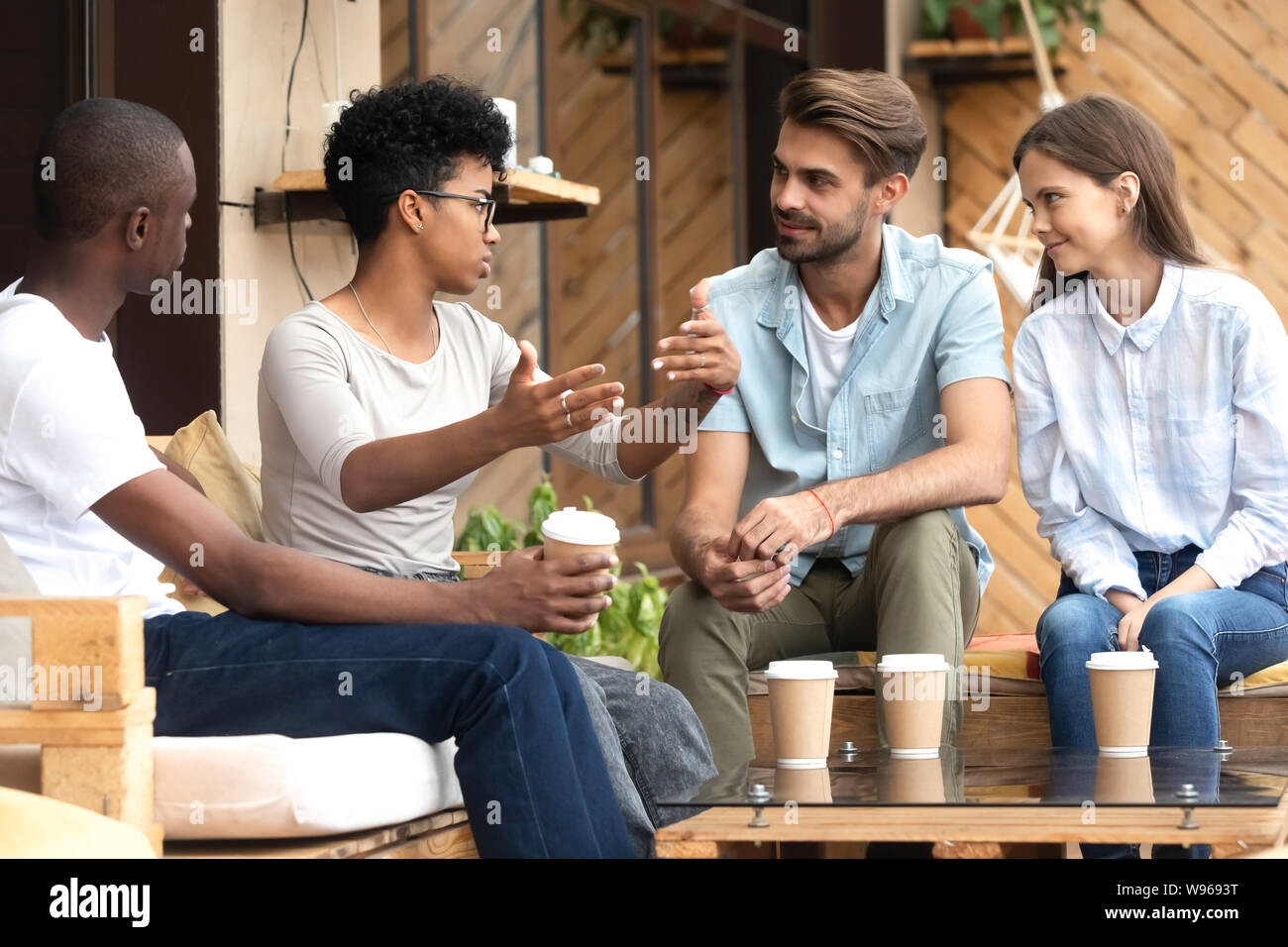 Diverse young people relax in cafe communicating Stock Photo - Alamy